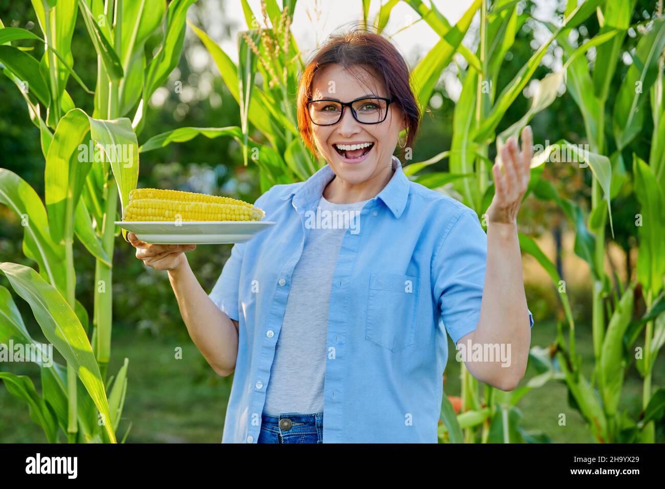 Middle-aged woman with boiled corn in plate Stock Photo - Alamy