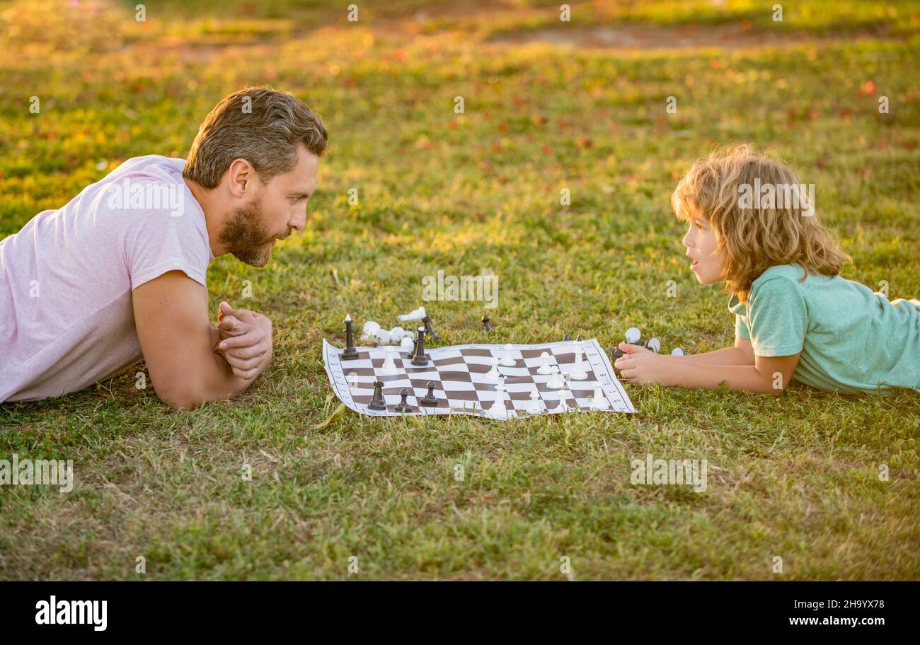 happy family of parent and son child playing chess on green grass in ...