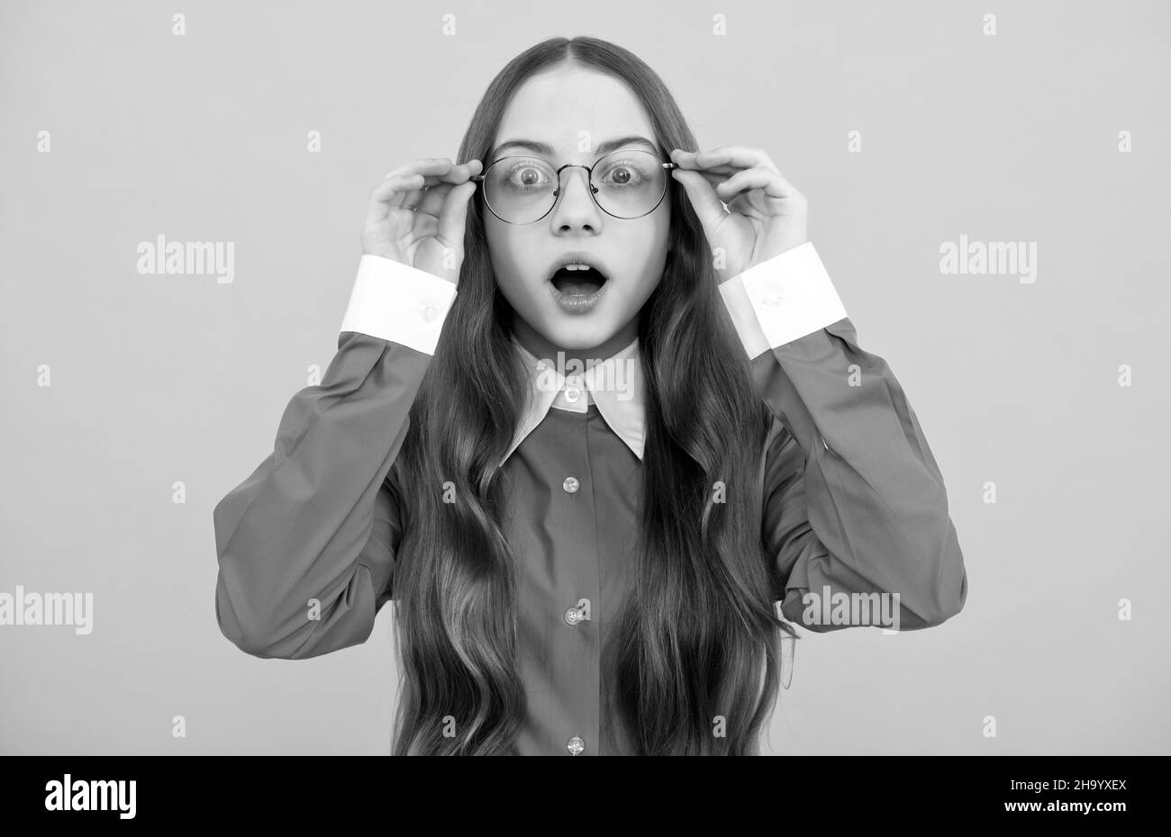 Shocked school aged girl child in spectacles with amazed look yellow ...