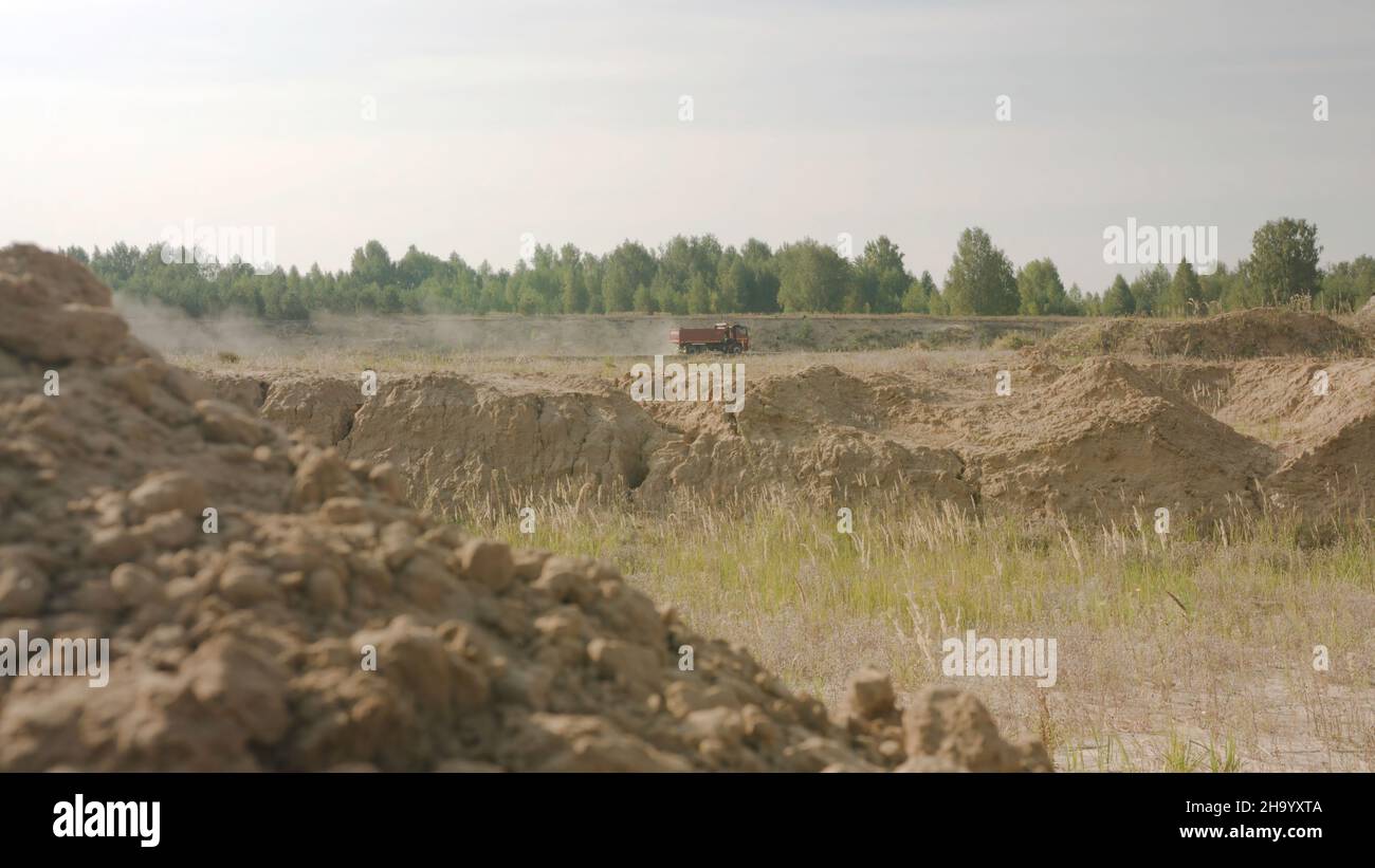 Truck driving on dusty road to quarry. Scene. On background of clay ...