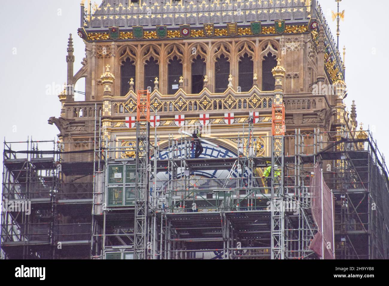 London, UK. 7th December 2021. Workers renovate the clock face as ...