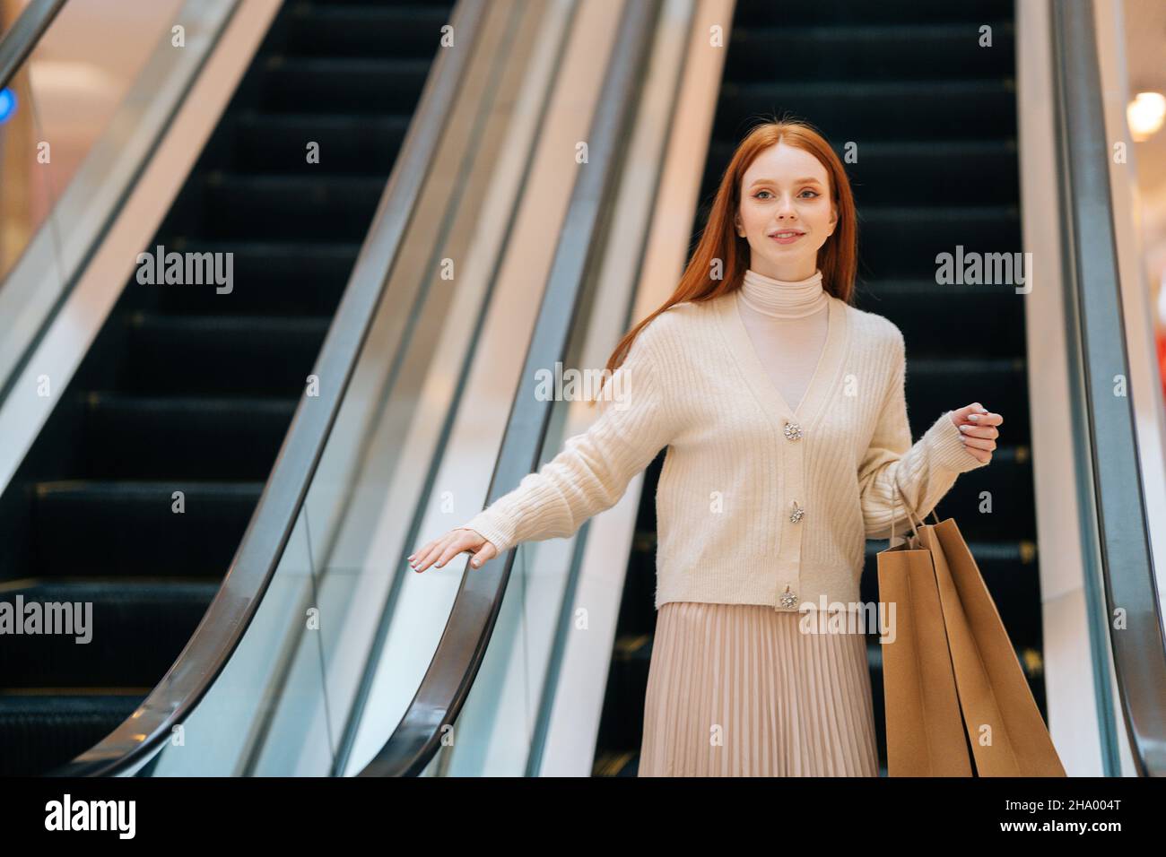 Portrait of attractive young woman holding on escalator handrail and ...