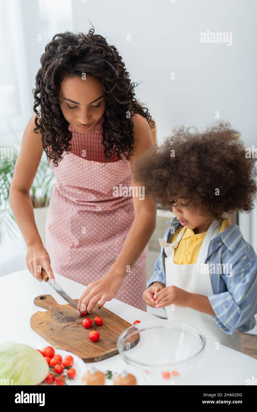 African american mom and kid cooking salad in kitchen Stock Photo - Alamy
