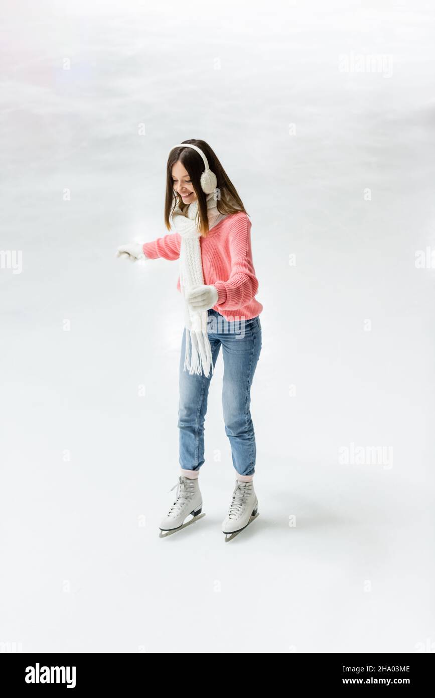 full length of positive young woman skating with outstretched hands on ...