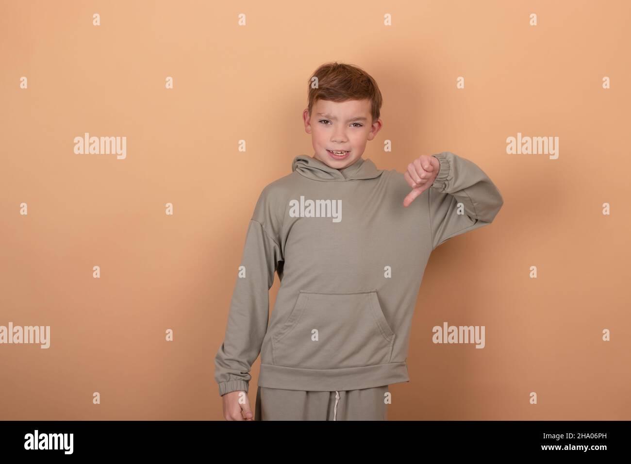 Beautiful teenager boy on isolated brown background showing dislike ...