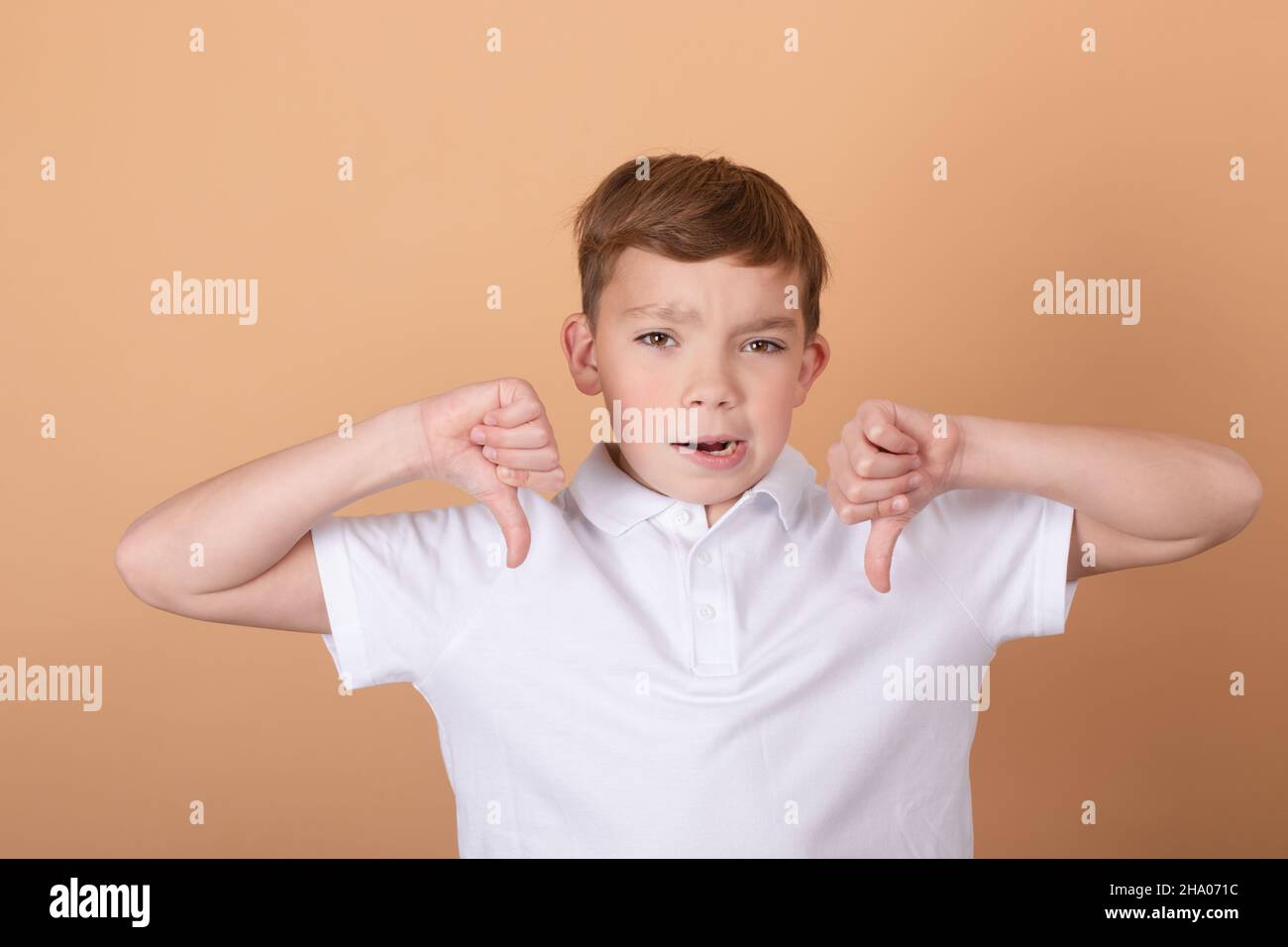 Beautiful teenager boy on isolated brown background showing dislike ...