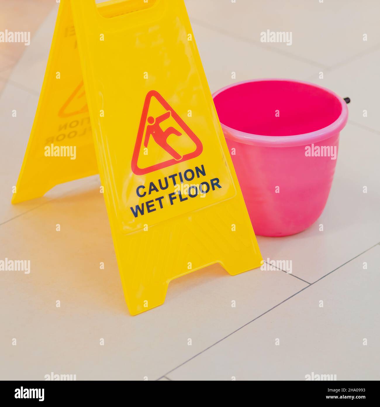 A yellow sign that says caution wet floor and pink plastic cleaning ...