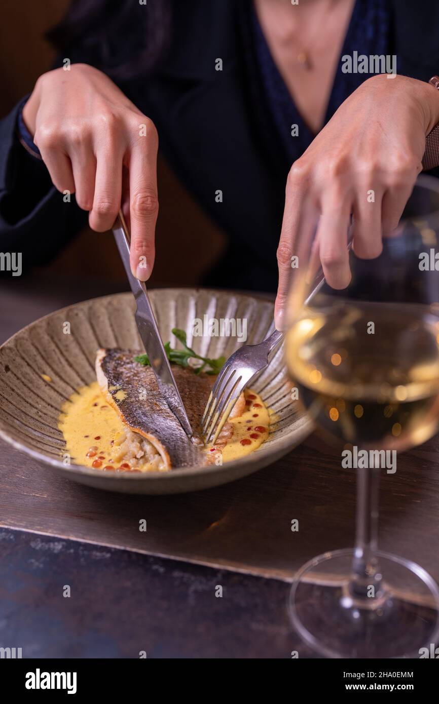 Female degustating deliciously prepared and elegantly served sea bass ...