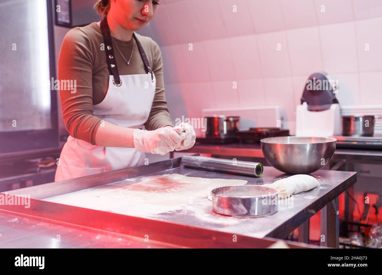 a female chef is working with a dough in the kitchen at a restaurant ...