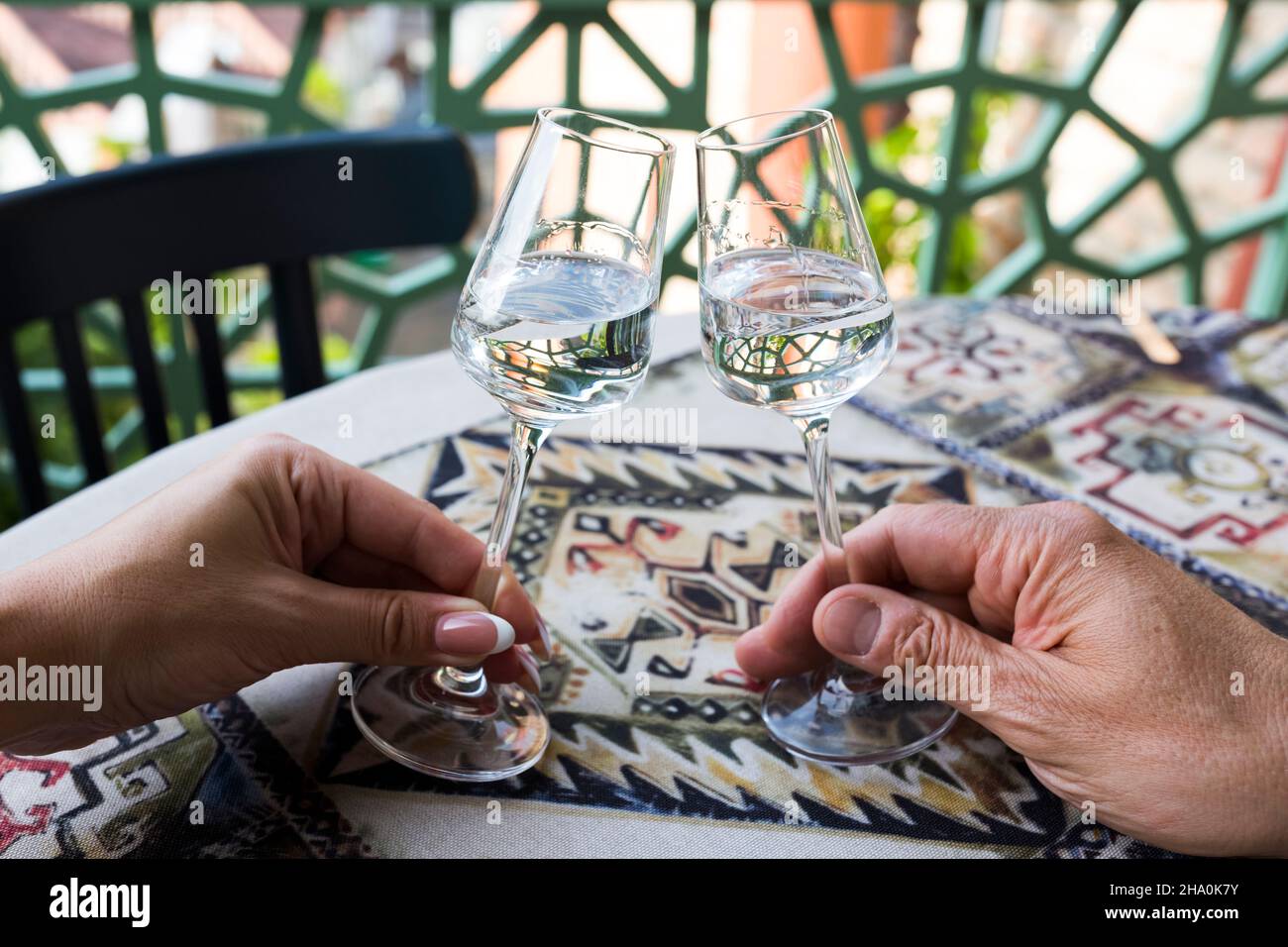 A woman's hand and a man's hand holds glasses with grappa, vodka ...