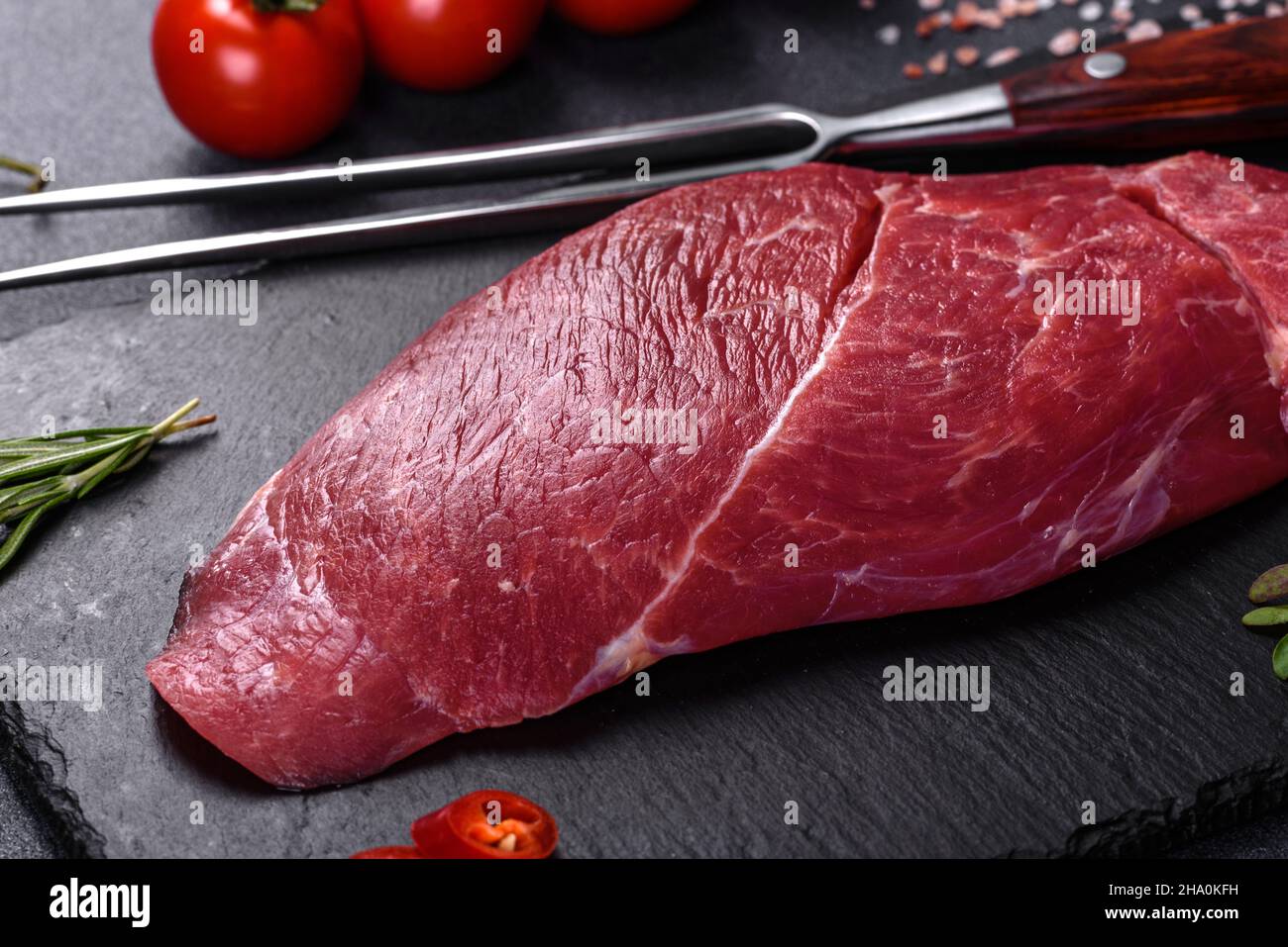 Raw fresh Chuck roll steak with herbs and salt on a cutting Board. Gray ...