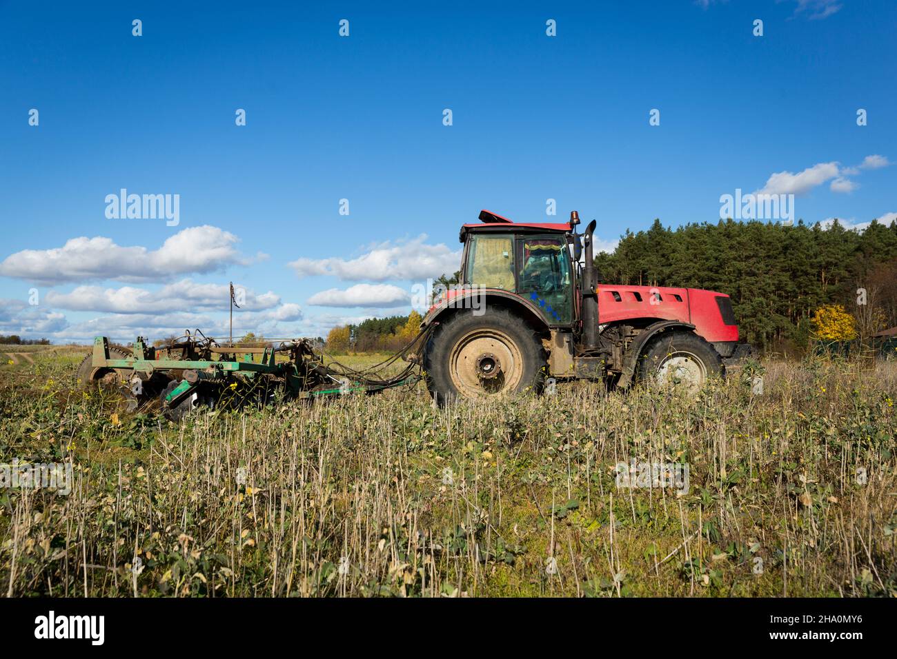 A modern red tractor in a field. Plowing a heavy tractor agricultural ...