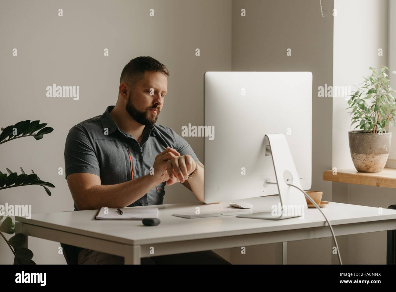 A man works remotely on a desktop computer. A guy with a beard is ...