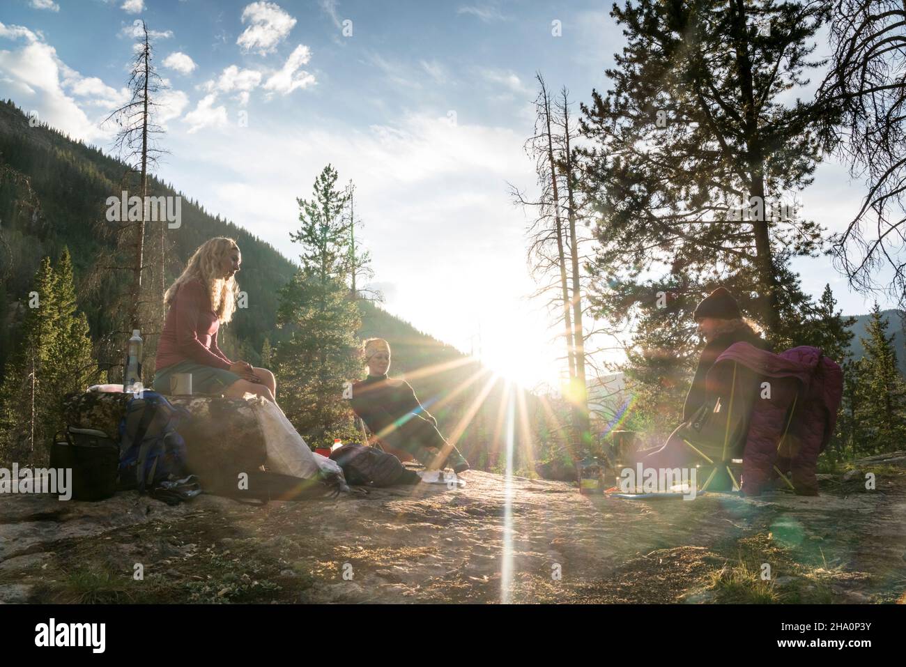 Three women enjoy a wilderness sunset in camp Stock Photo - Alamy