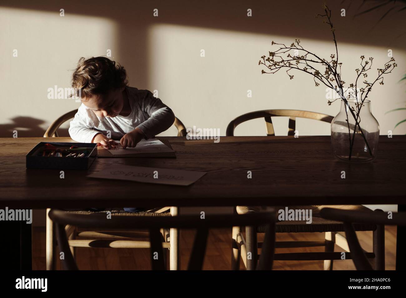 Little kid drawing at home alone lit by the sunrise Stock Photo - Alamy