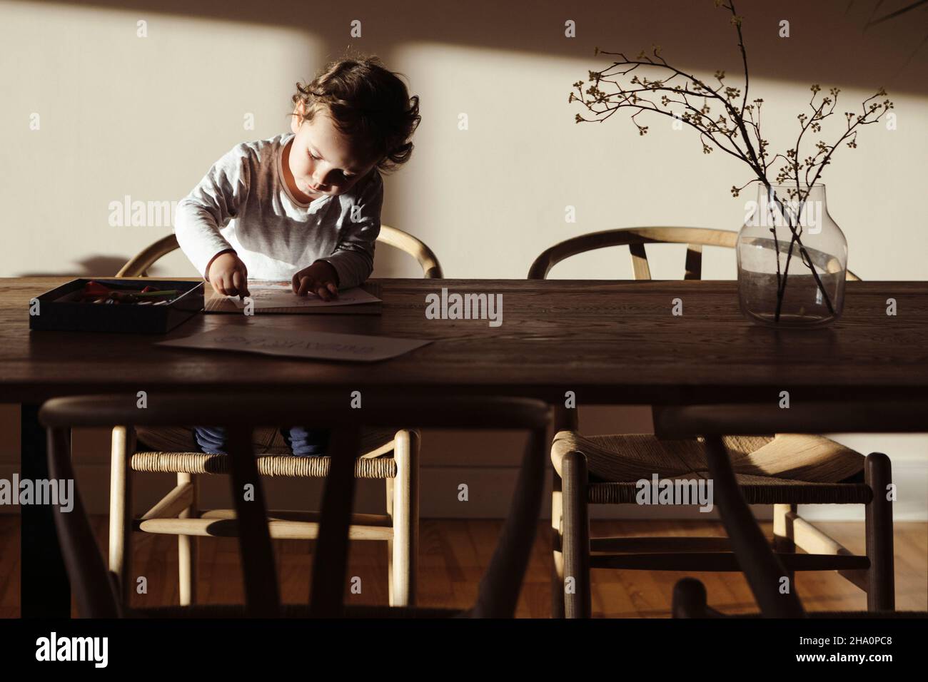 Little kid drawing at home alone lit by the sunrise Stock Photo - Alamy