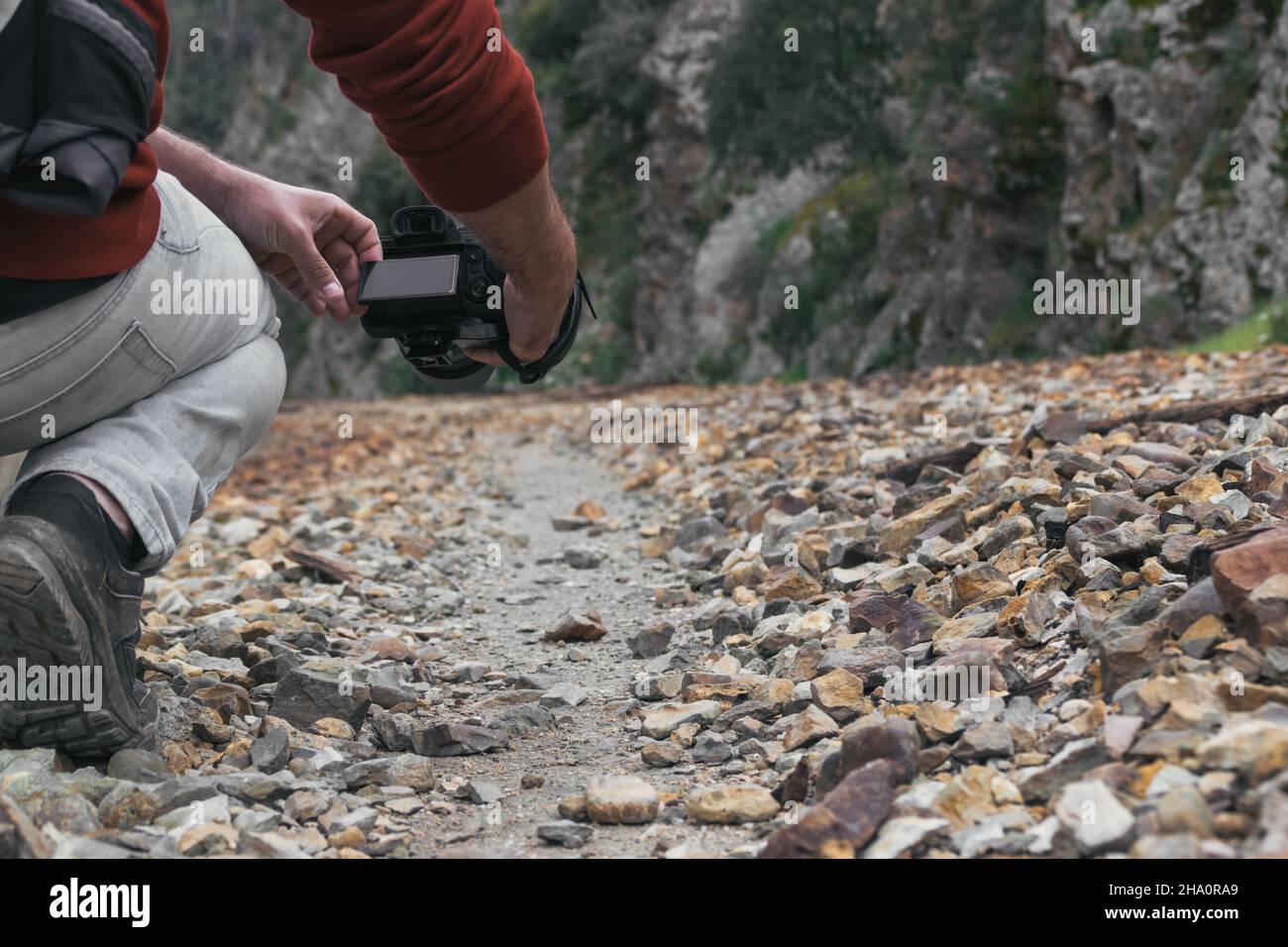 Young photographer taking a picture with a camera on a stone path ...