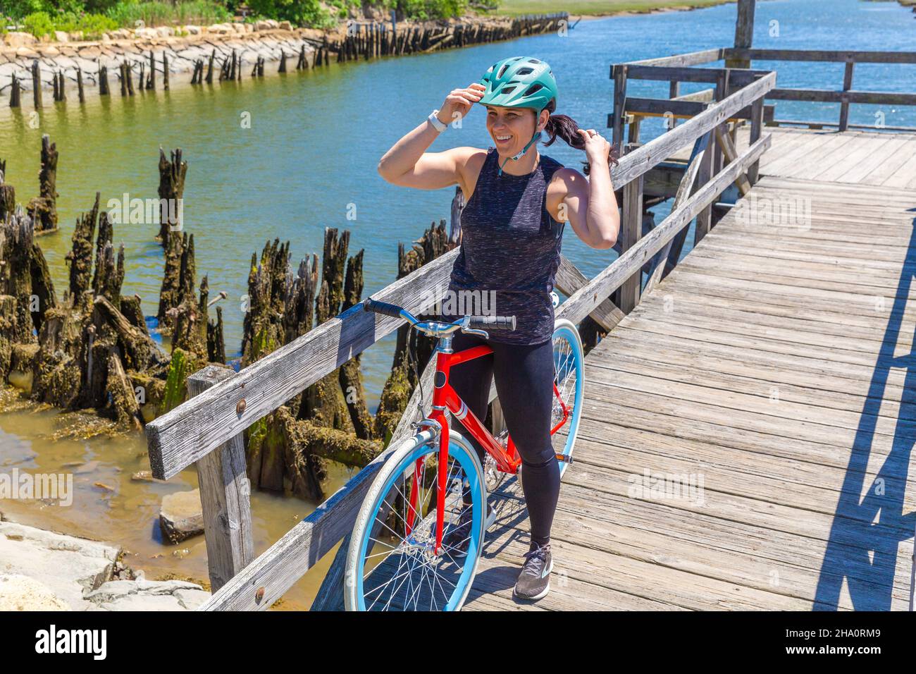 Woman with Ponytail Adjusts Bike Helmet on Dock Near Water Stock Photo ...
