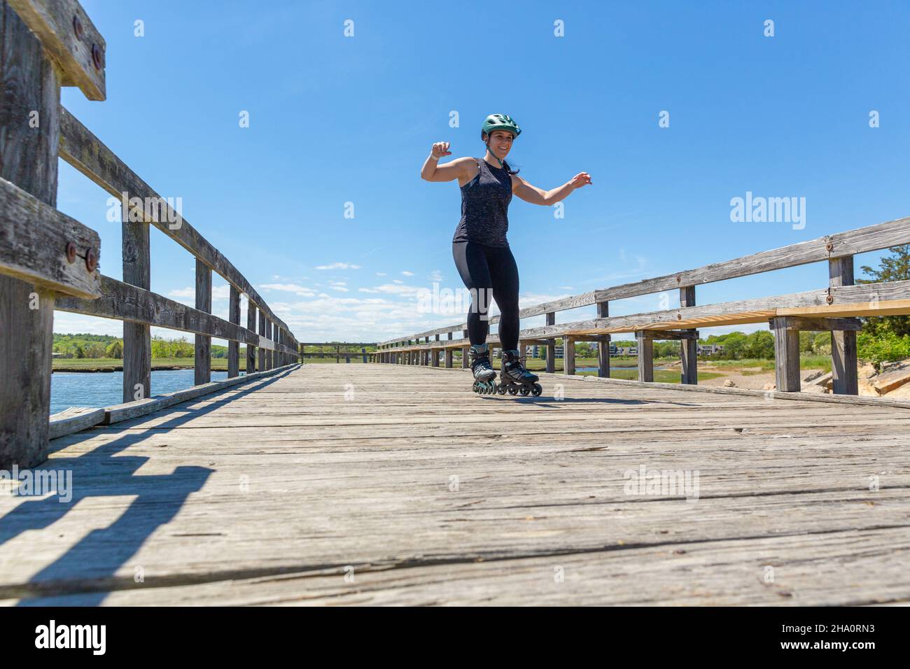 Woman Wobbles on Rollerblades on Dock over Ocean Stock Photo - Alamy