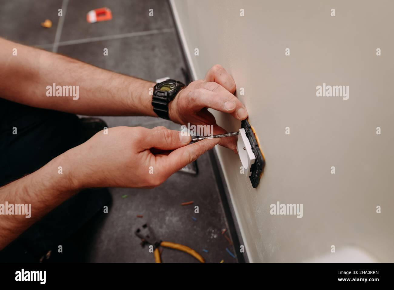Electrician installs socket in wall of home Stock Photo - Alamy