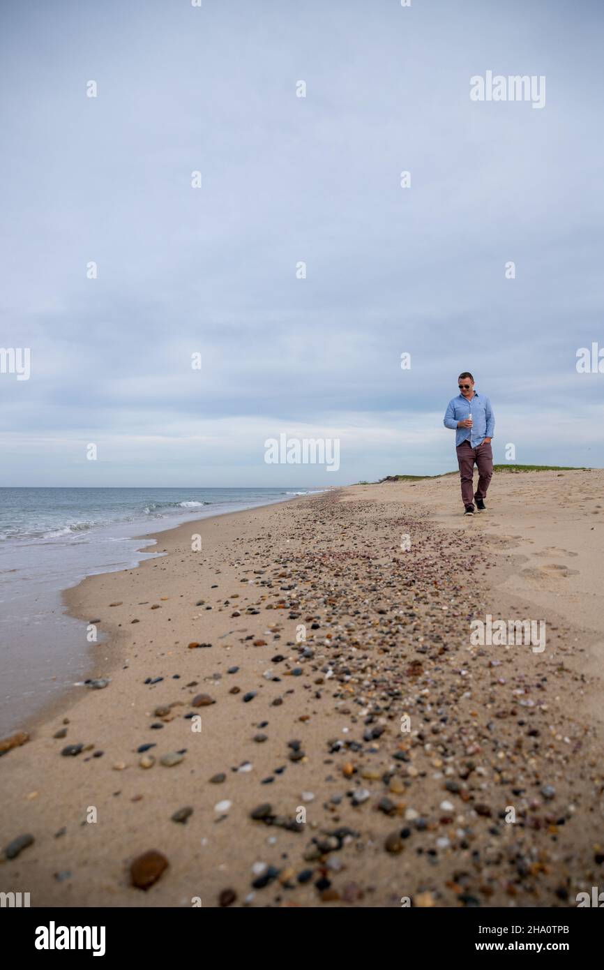 Man walking along sandy beach shoreline on Nantucket Island Stock Photo ...
