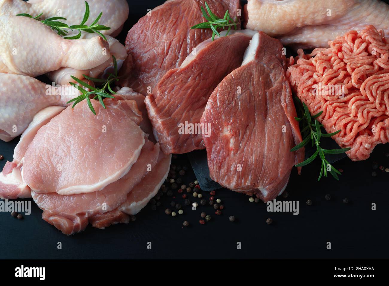 Various types of fresh meat: pork, beef, turkey and chicken on a black ...