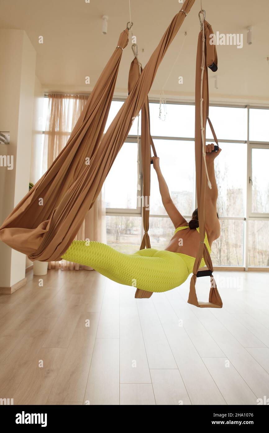 Vertical rear view shot of a female gymnast doing aerial yoga exercise ...