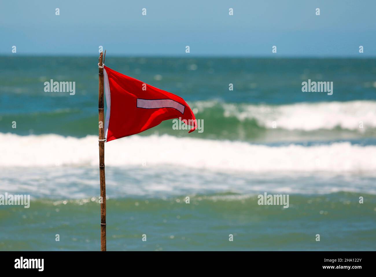 Red flag life guard danger warning sign on the beach. No swimming it's ...