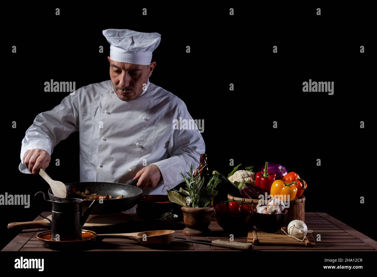 Male cook in white uniform and hat with ladle mixes the ingredients ...
