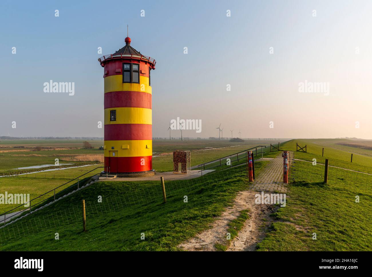The striped red and yellow Pilsum lighthouse on the shores of the ...