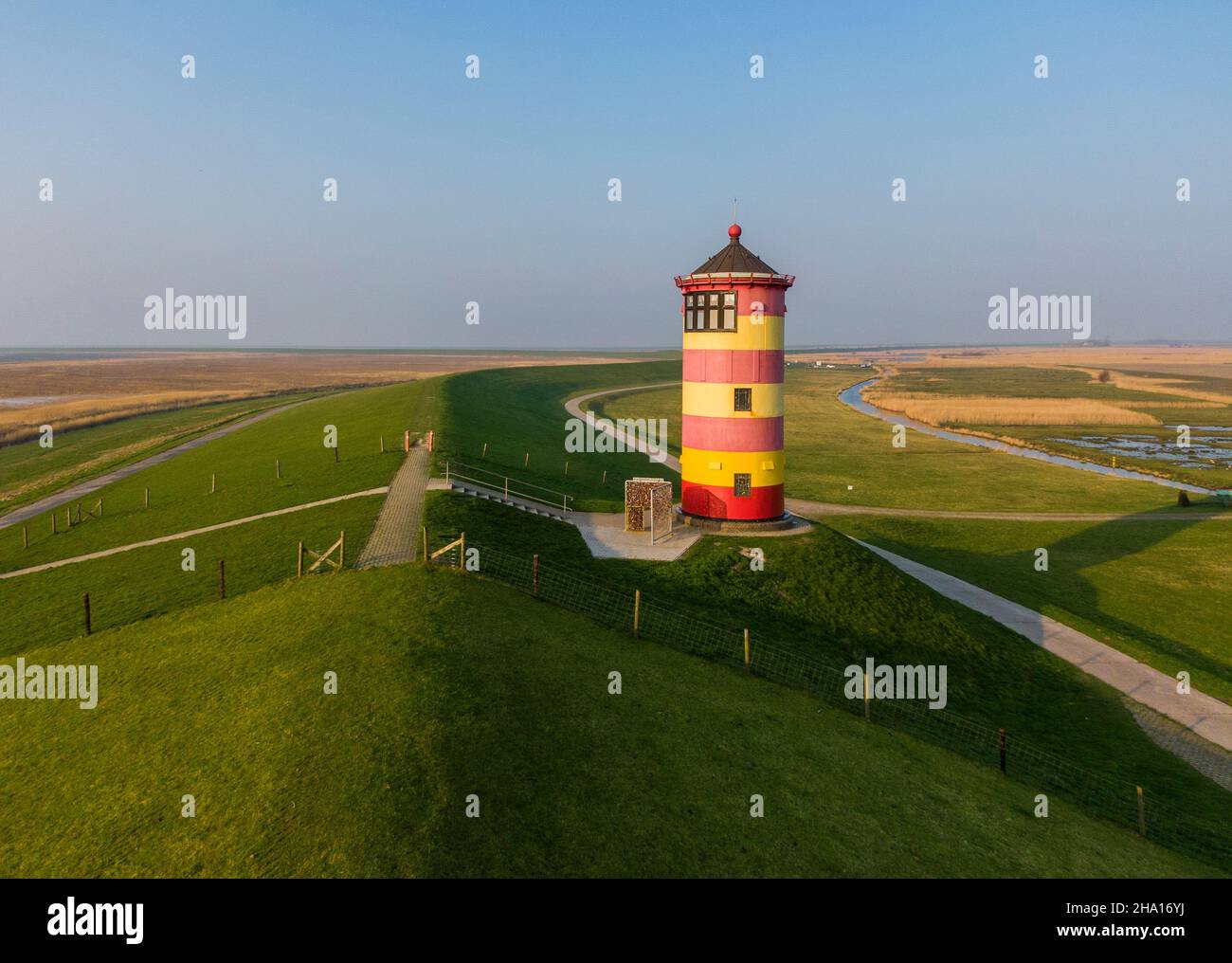 The striped red and yellow Pilsum lighthouse on the shores of the ...