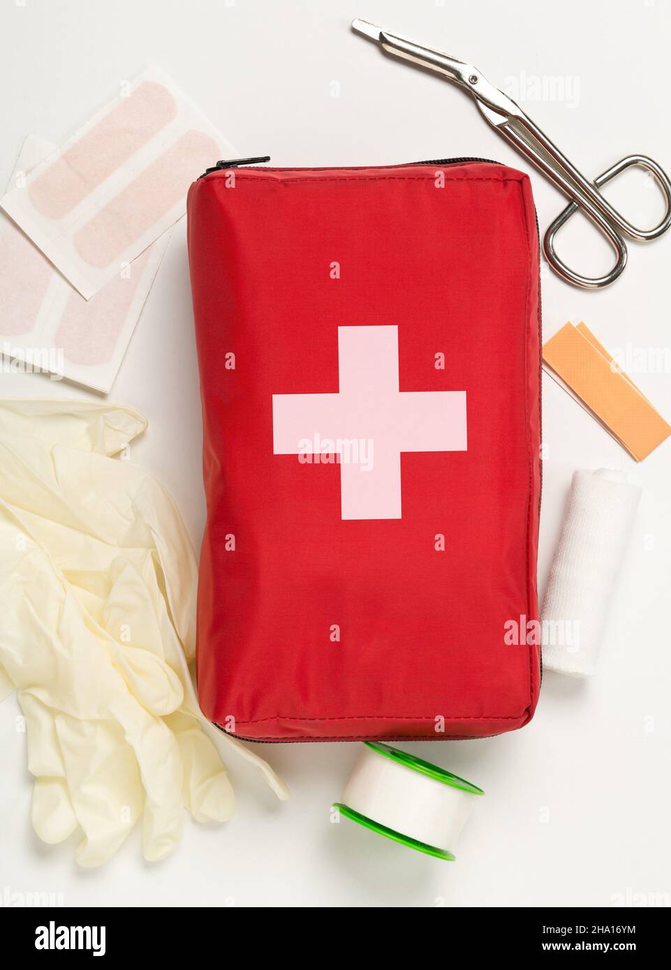 Red first aid medical kit bag with scissors, tape and gloves top view ...