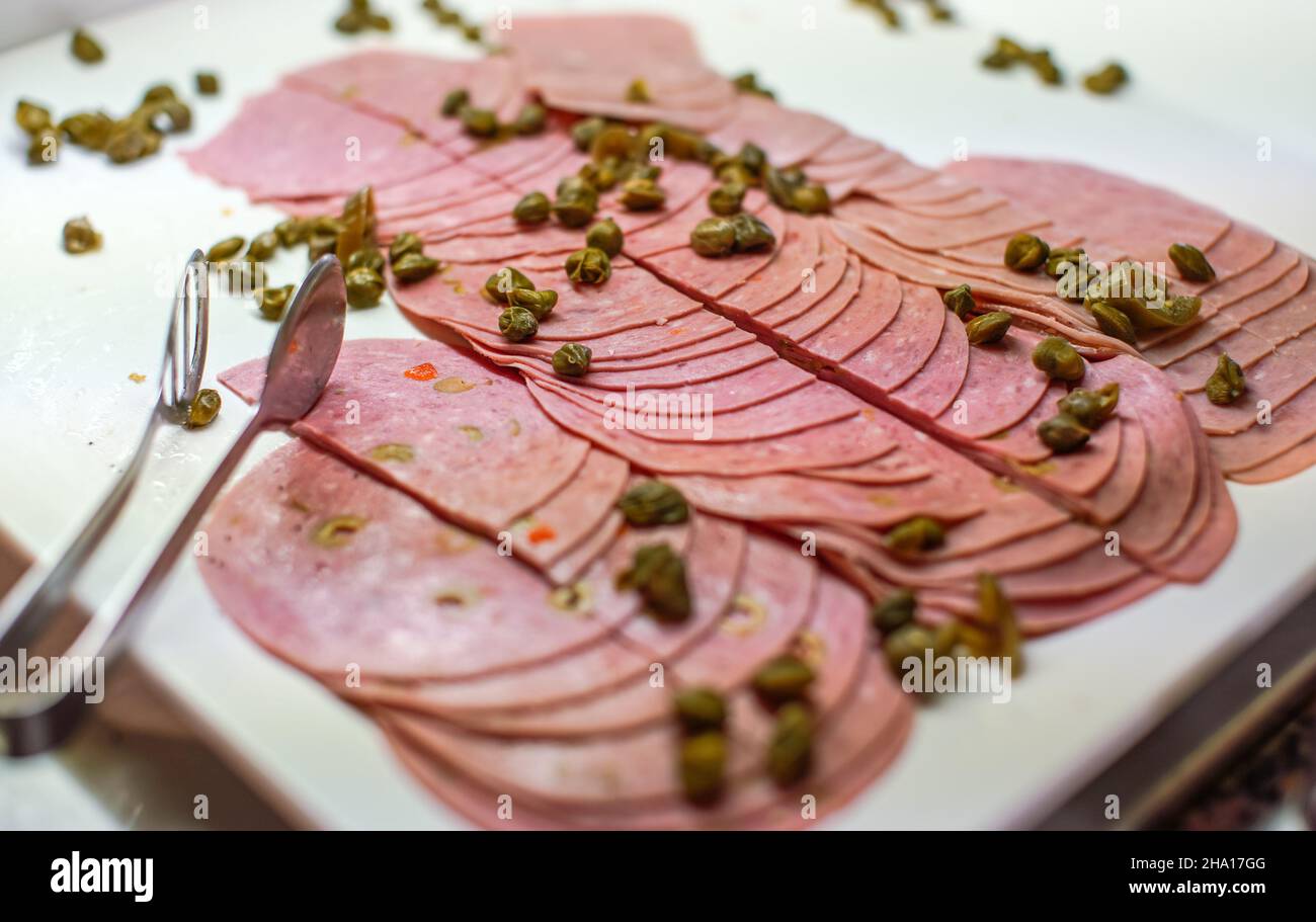 Slices of ham with green capers on white plate displayed at all ...