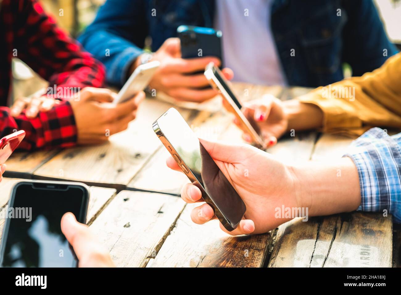 Group of friends checking social media on smartphones at restaurant or ...