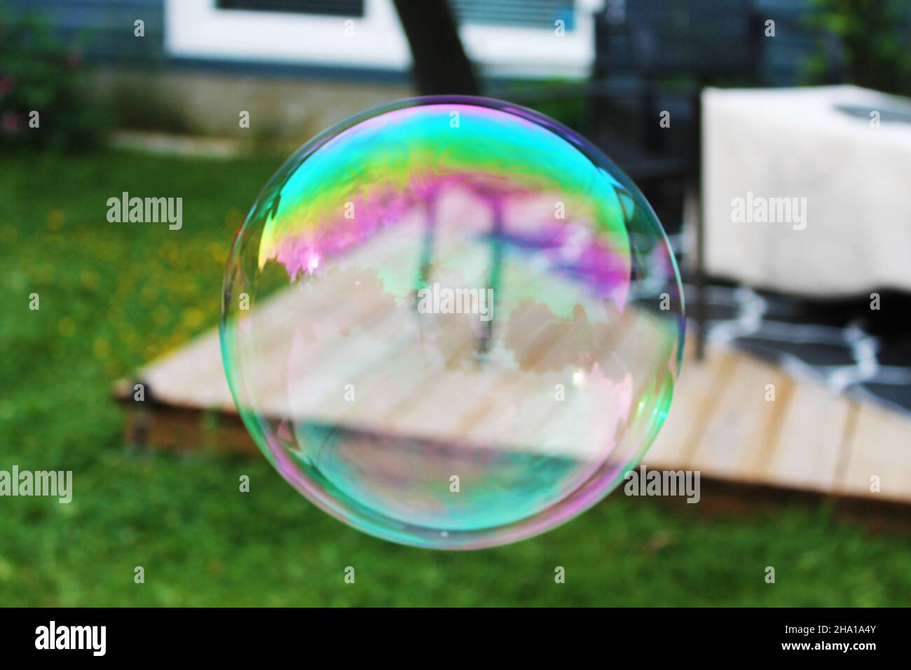 Closeup of a large bubble outside, garden in background and reflected ...
