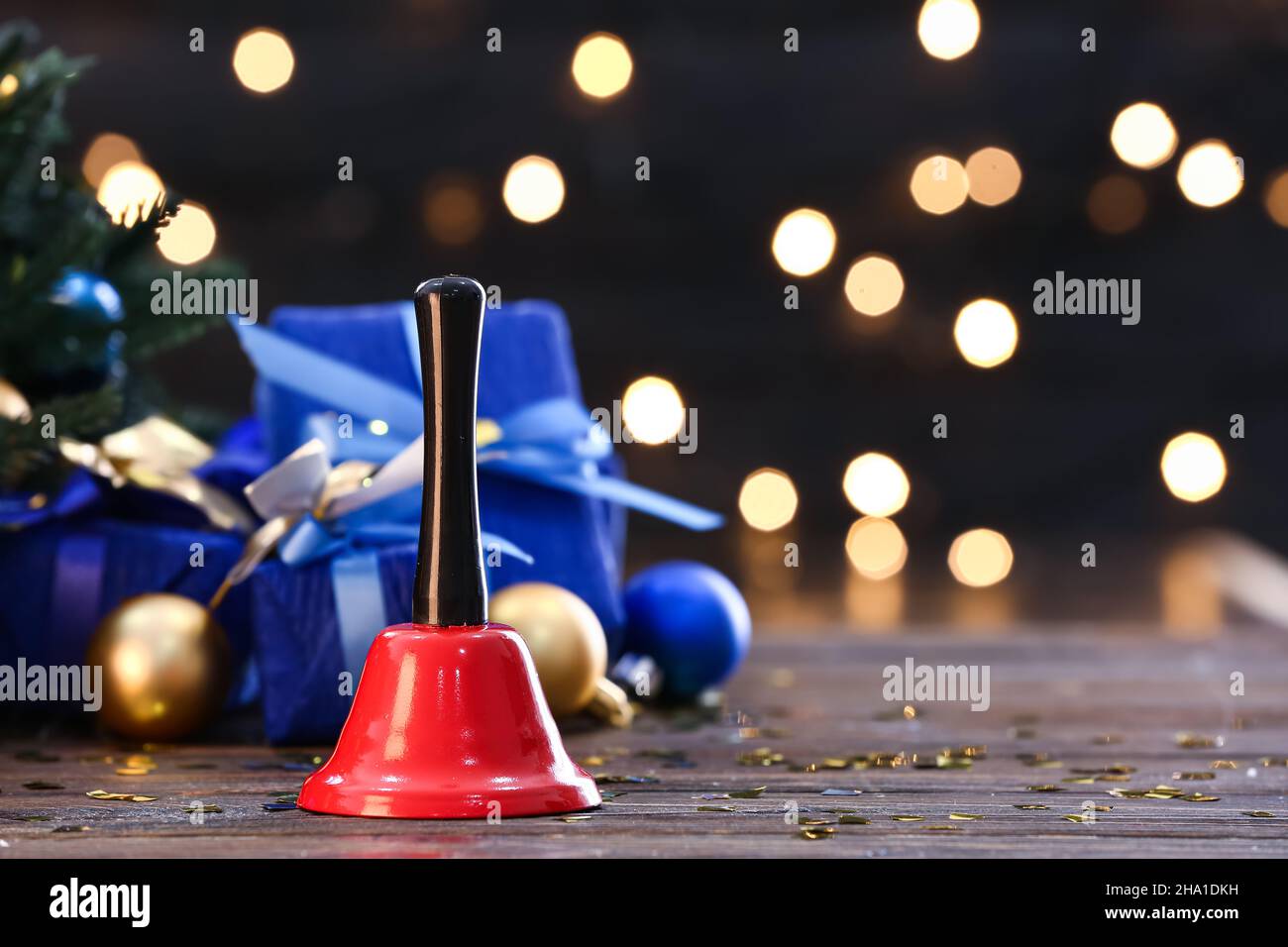 Red Christmas bell on wooden table against blurred lights Stock Photo ...