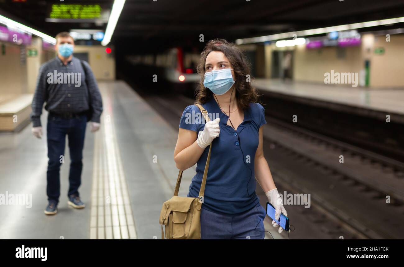 Female in face mask and earphones on subway platform Stock Photo - Alamy