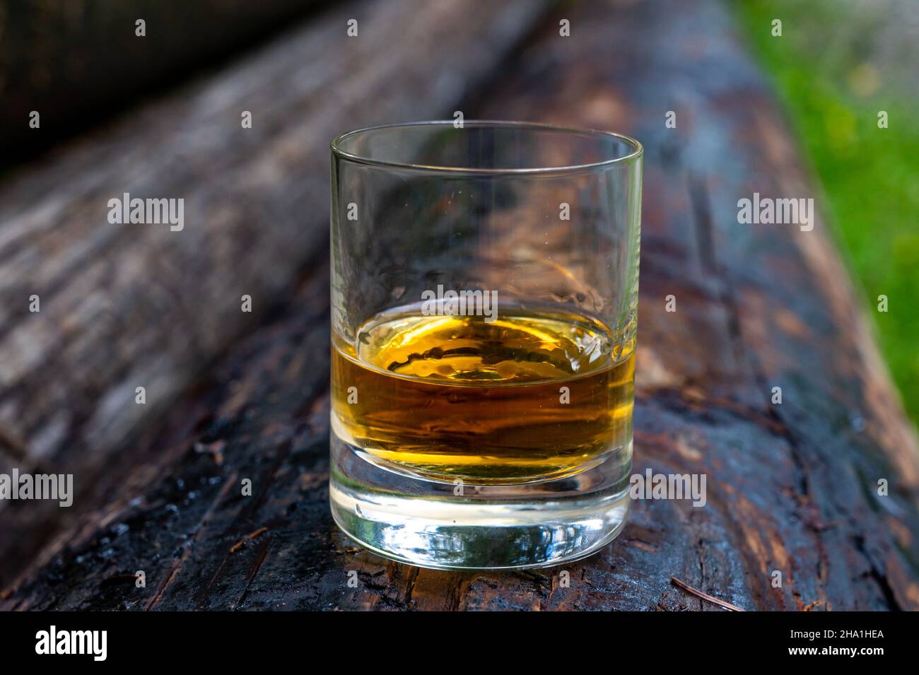 Glass of strong scotch single malt whisky on old log soaked in creosote ...