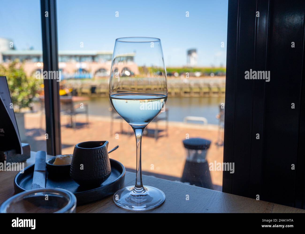 Glass of dry white wine served in cafe with view on harbour of ...