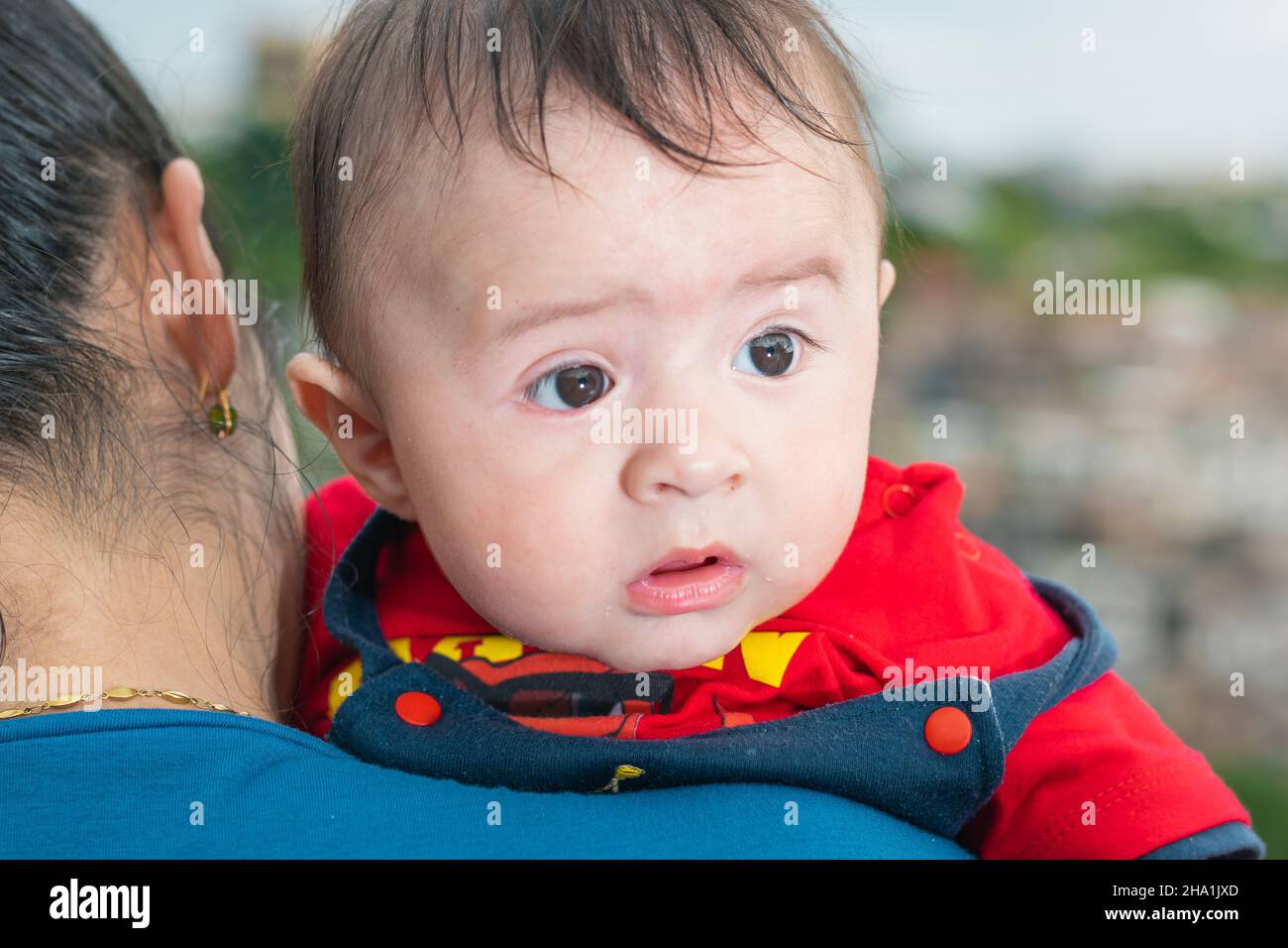 beautiful latin baby peeking his head over his mother's shoulder, big ...