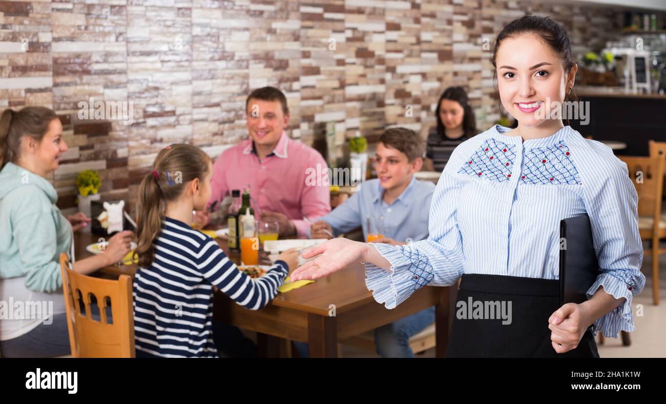 Charming young waitress warmly welcoming guests to family cafe Stock ...