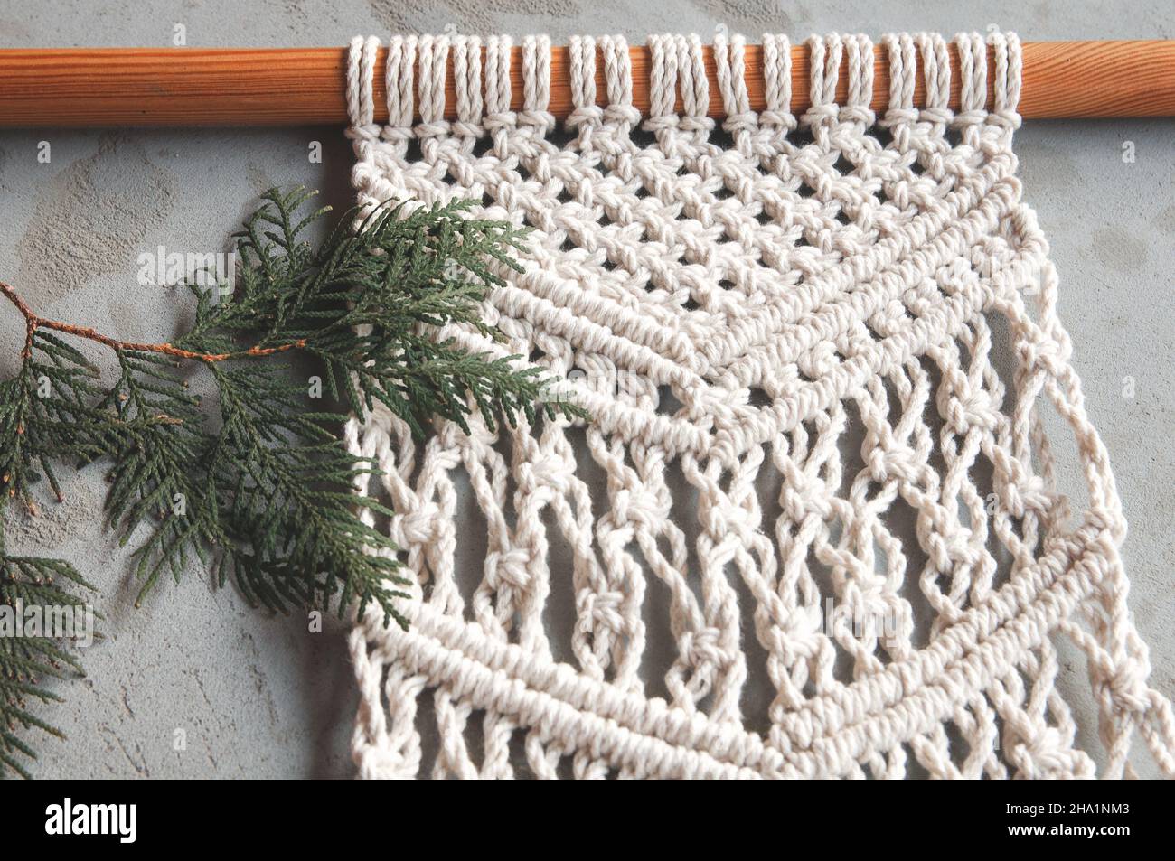 wall decoration handmade macrame on concrete background with fir branch ...