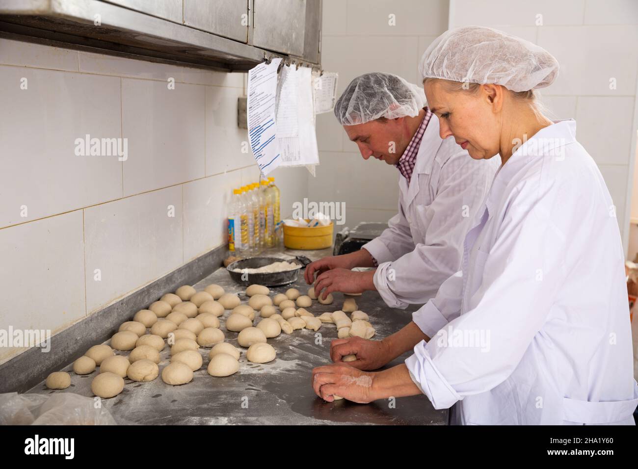 Man and woman cook pastry from raw dough in the kitchen of bakery Stock ...