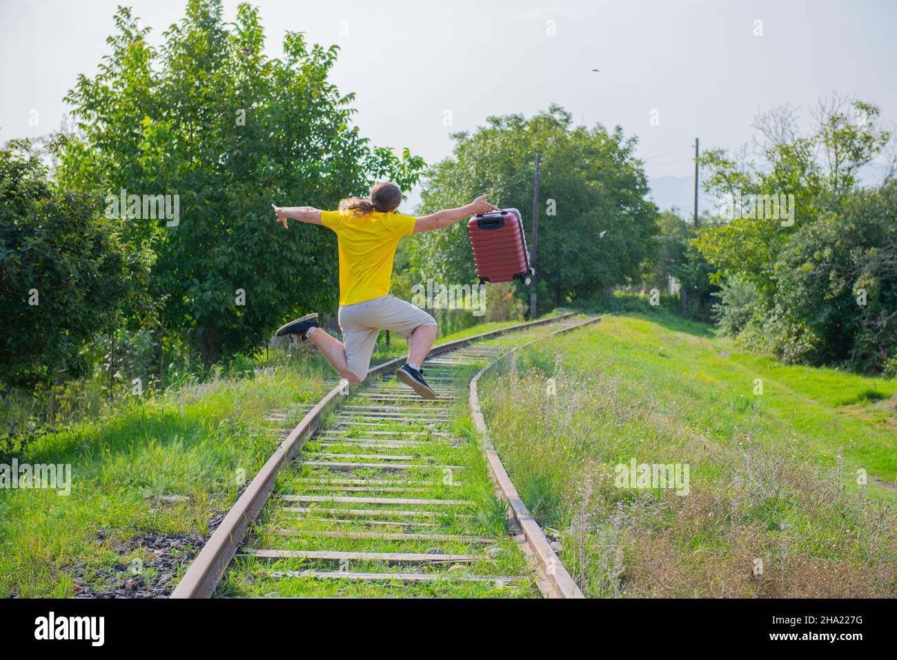 crazy man with a suitcase jumping on the railroad Stock Photo - Alamy