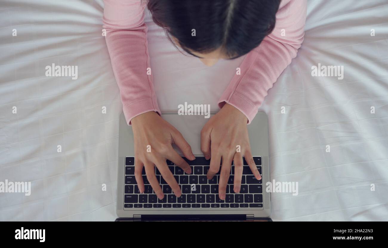 Hands of woman typing on laptop keyboard on bed Stock Photo - Alamy