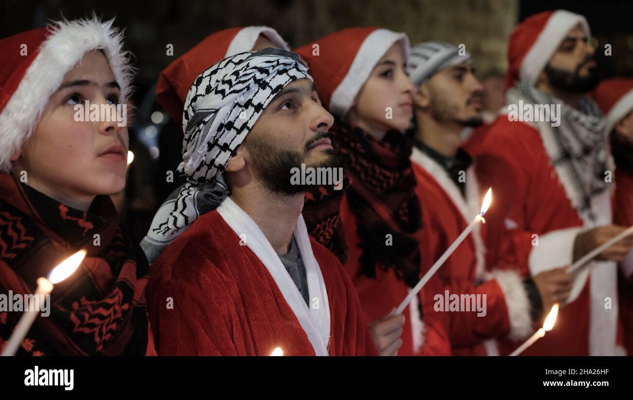 Young Palestinian Christians in Santa costumes hold candles as they ...