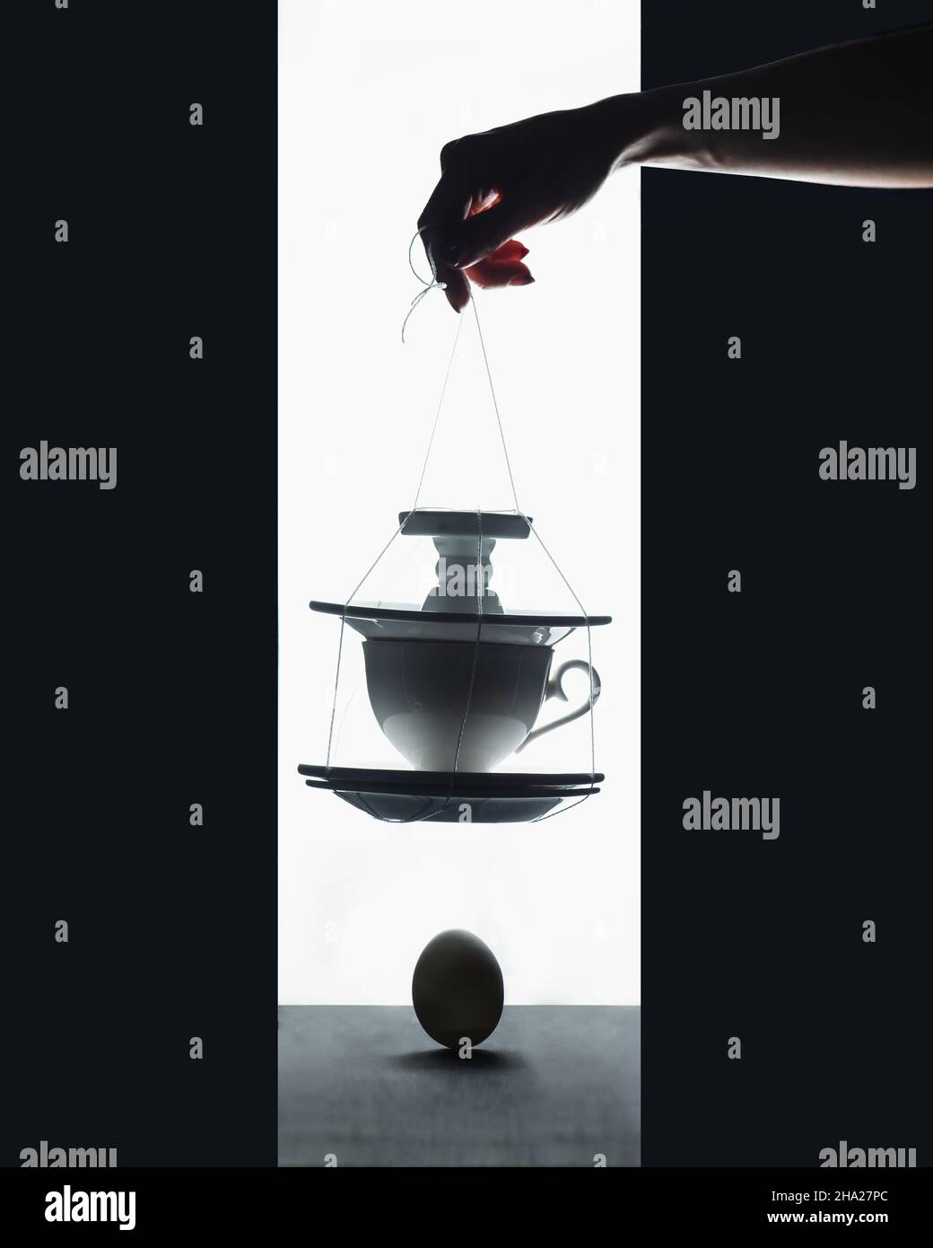 Danger of falling, stack of dishes and cups hanging over an egg ...