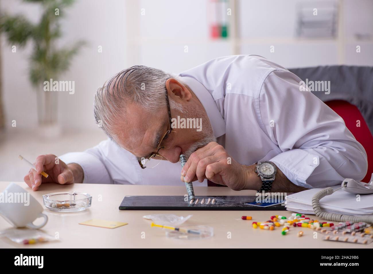 Old male drug addicted employee sitting at workplace Stock Photo - Alamy