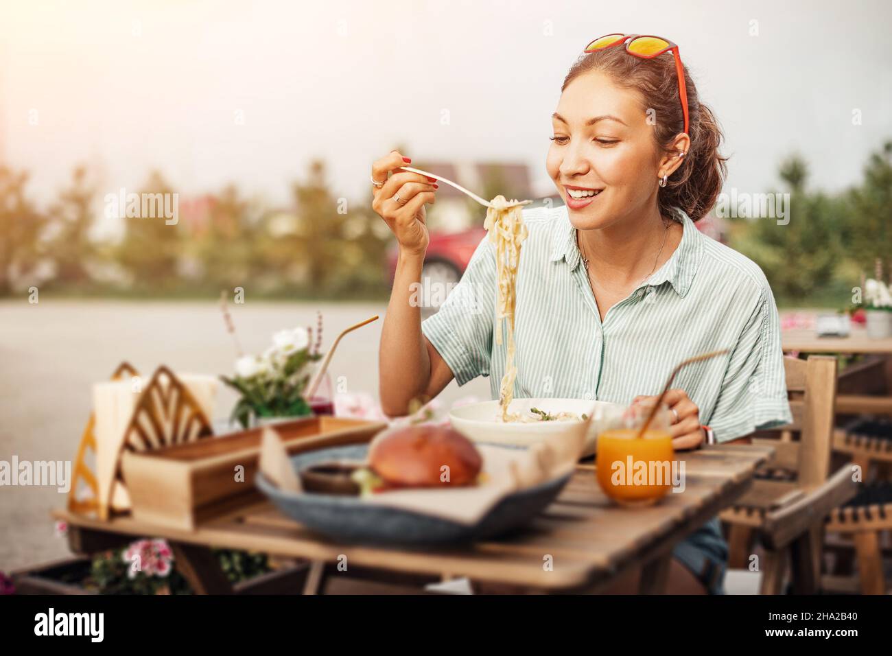 Happy asian woman eating itallian spaghetti or pasta outdoors in open ...