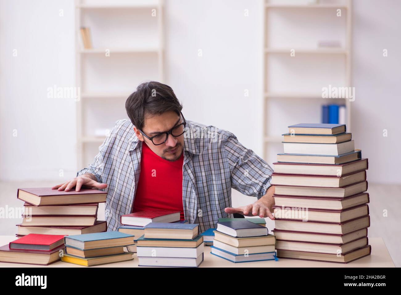 Young student and too many books in the classroom Stock Photo - Alamy